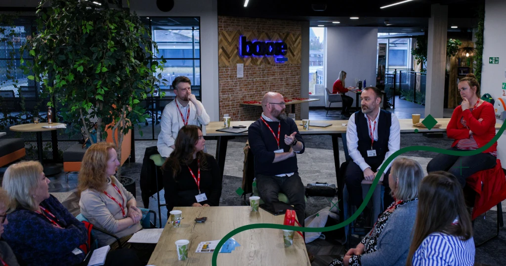 A group of people in smart casual business attire sat around a table ...